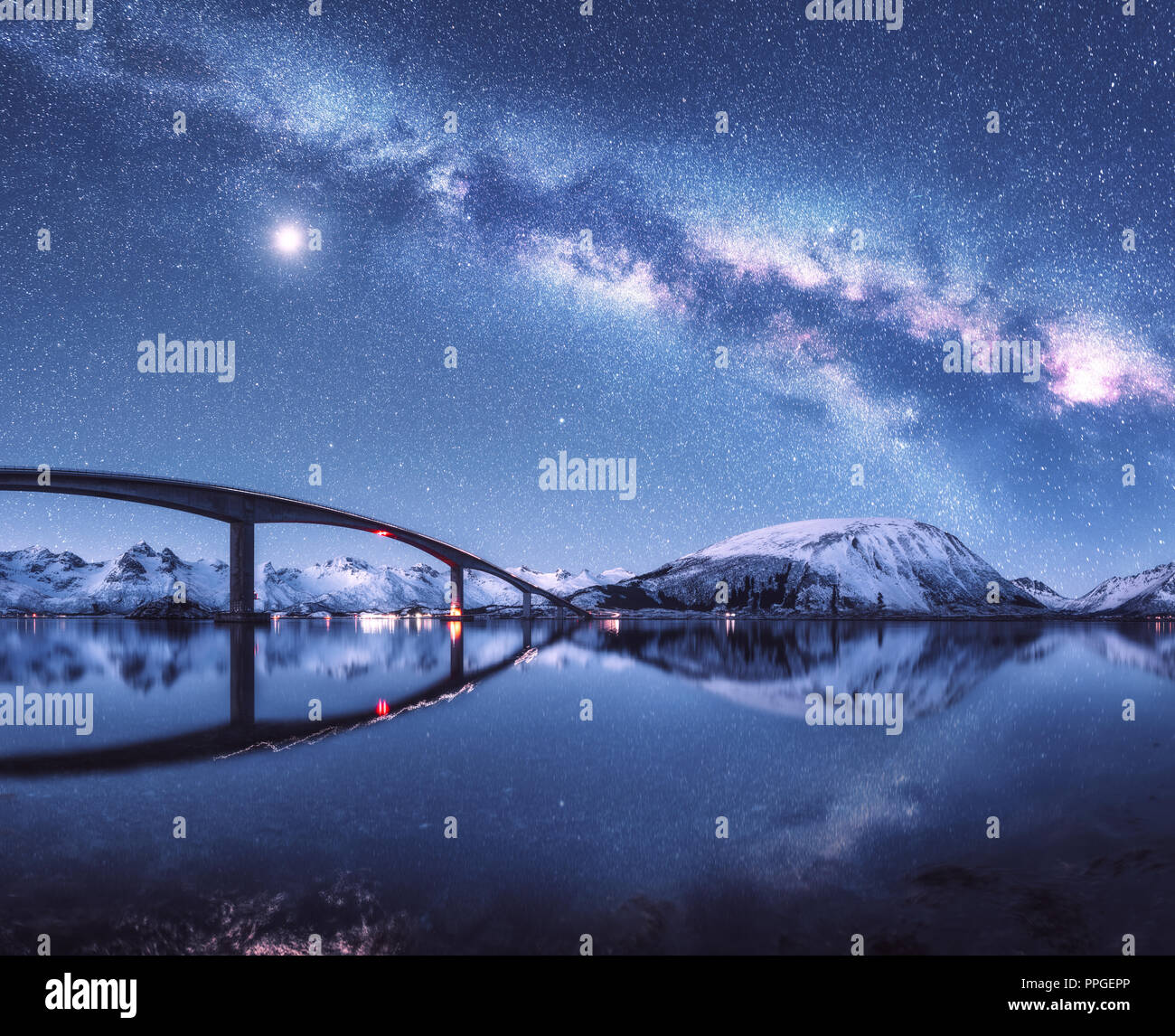 Bridge and starry sky with Milky Way over snow covered mountains ...