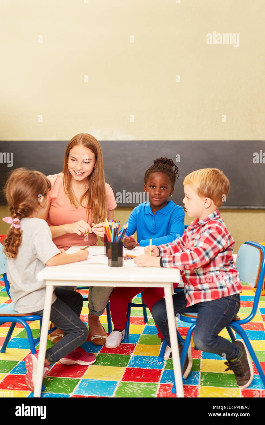 Multicultural children group and educator while painting together in ...