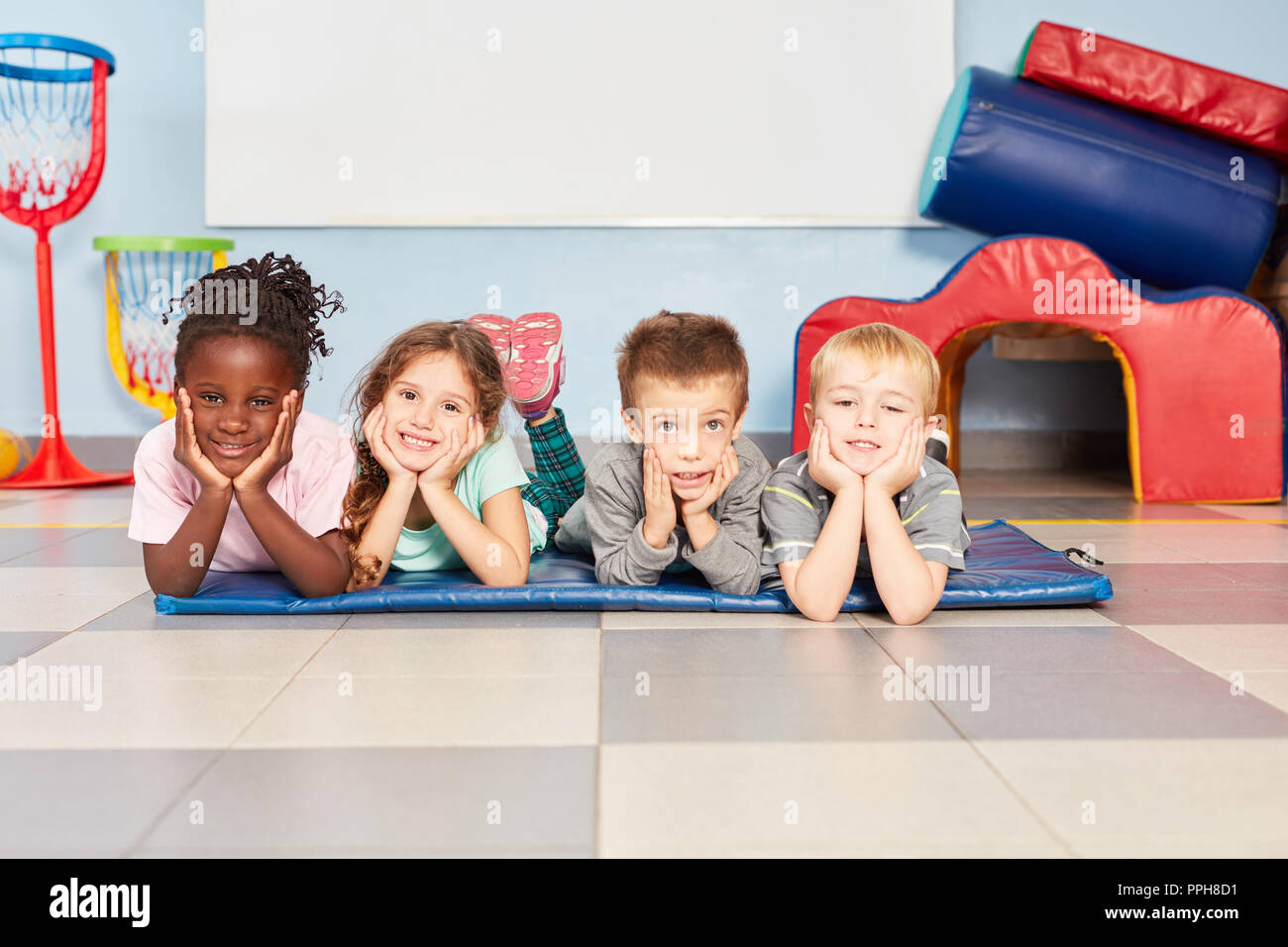 Four multicultural kids as friends in the gym in kindergarten or ...