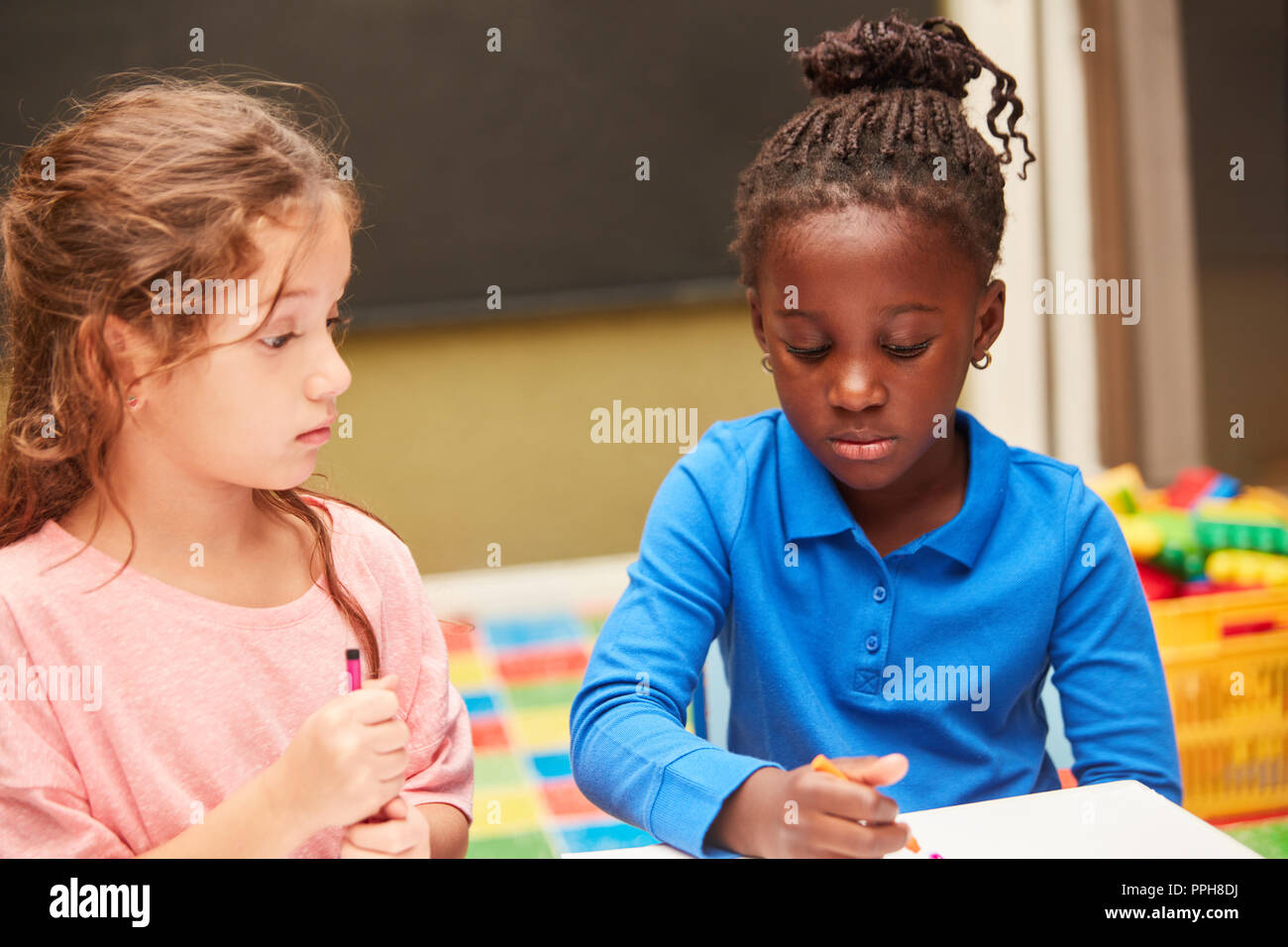 Two girls are painting together in the drawing class in the ...