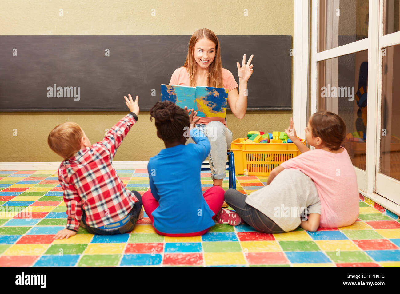 Woman as a teacher and children have fun together while reading aloud ...
