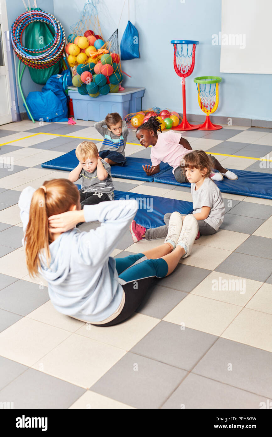 Group of kids does gymnastics together with sports teacher in the gym ...