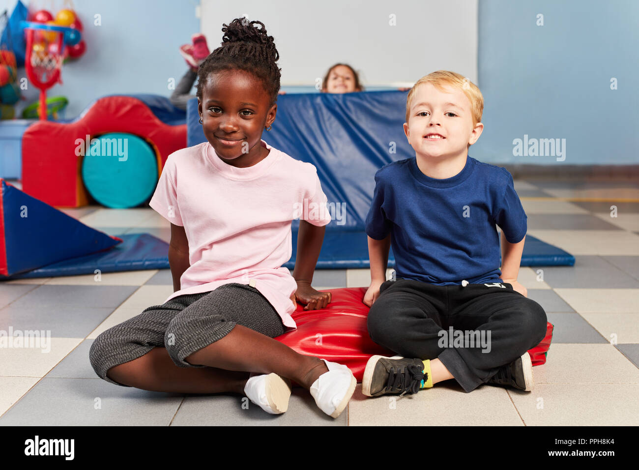 Two kids playing kid sports in multicultural kindergarten in the gym ...