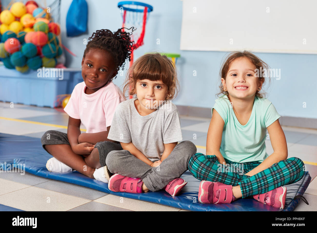 Three girls as friends are sitting in the gym in multicultural ...