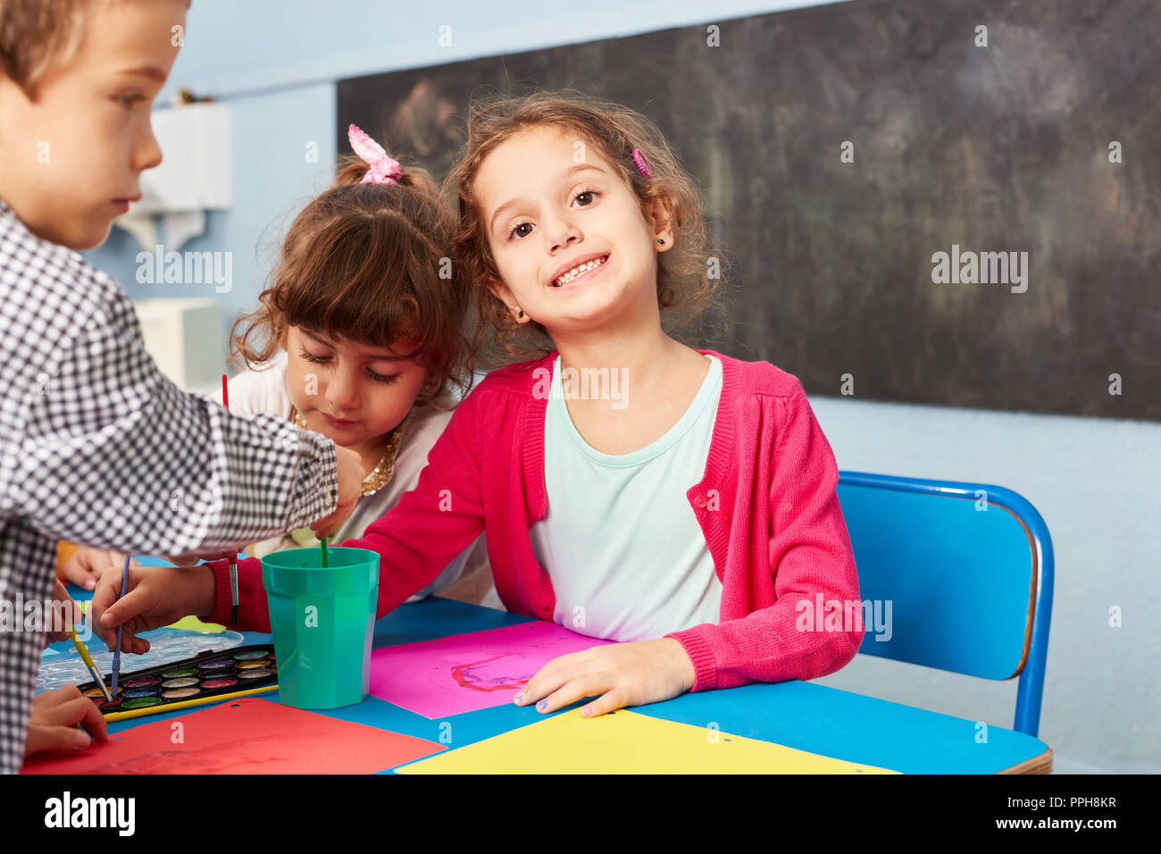 Happy girl in creative painting class in kindergarten together with ...