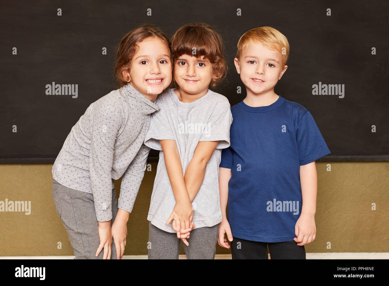 Three children as students and good friends in front of a blackboard in ...