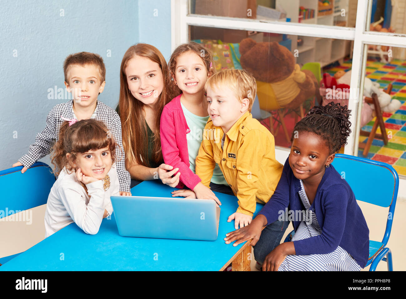 Teacher and children at laptop Computer in a computer course in ...