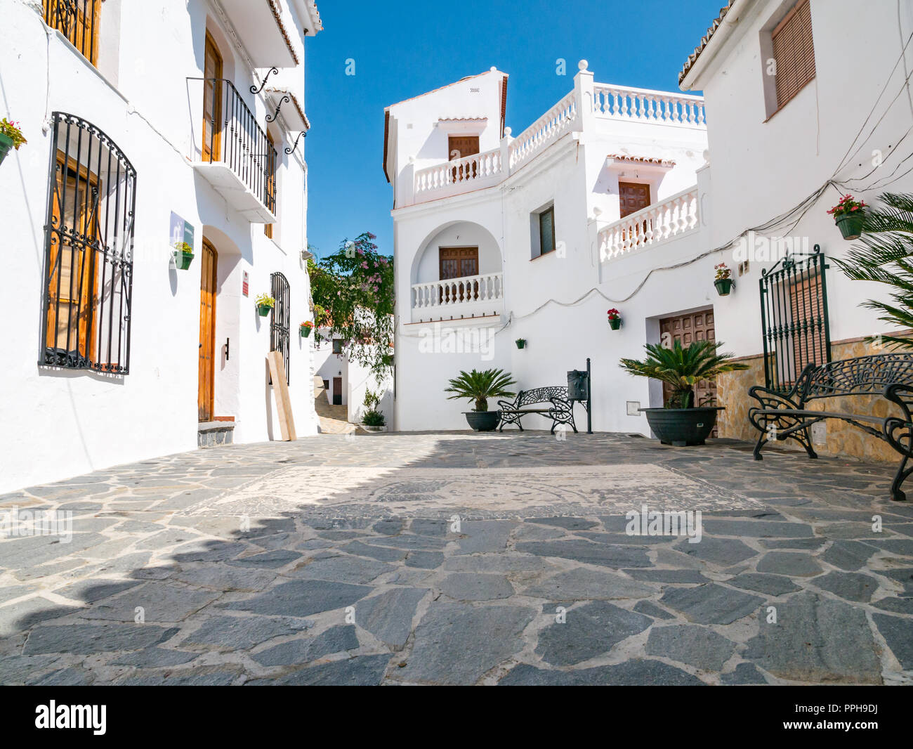 Pretty square with white houses and benches, old Moorish village of ...