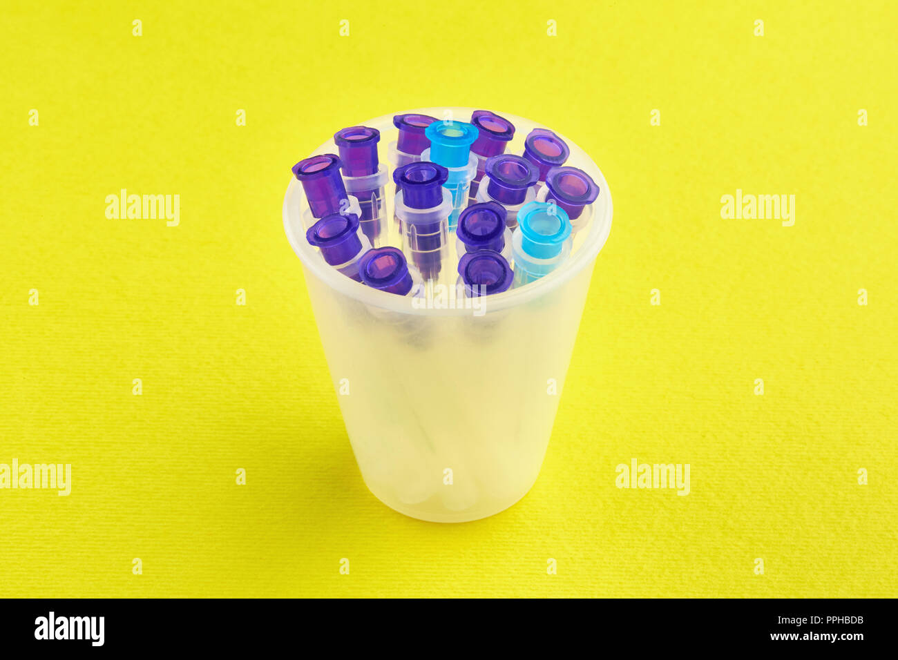 Colorful syringe needles in measuring glass on yellow background Stock ...