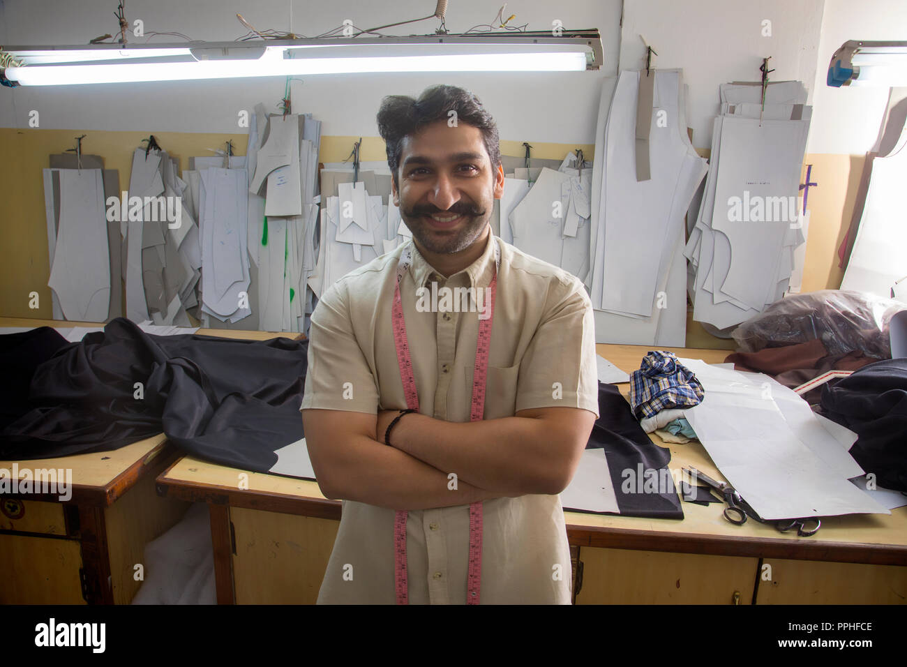 Happy looking tailor standing in his workshop with arms crossed Stock ...