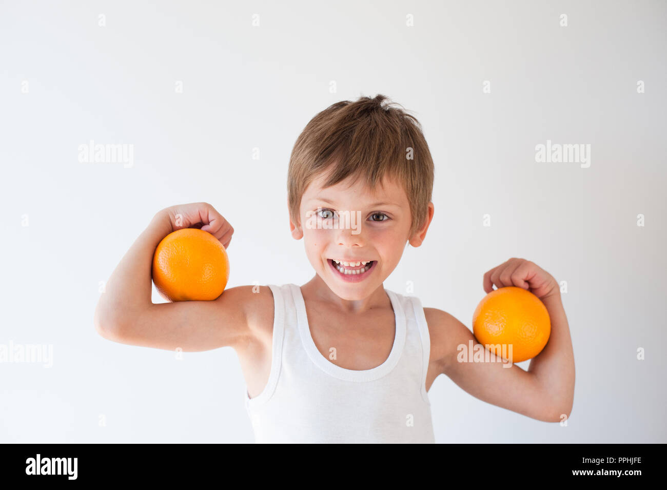 happy delightful smiling little strong child with fruit orange on his ...