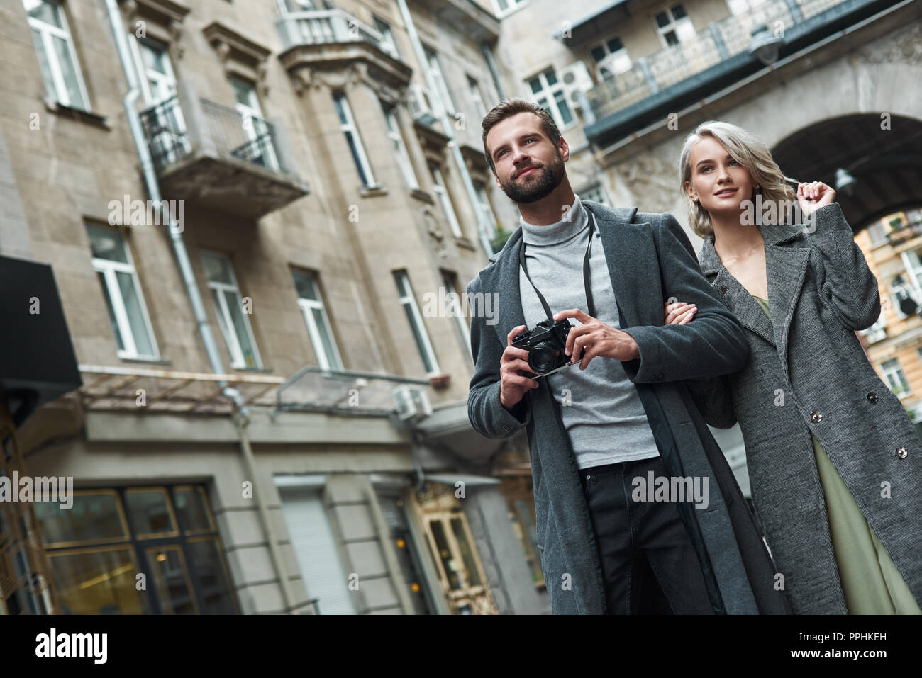 Romantic date outdoors. Young couple walking on the city street taking ...