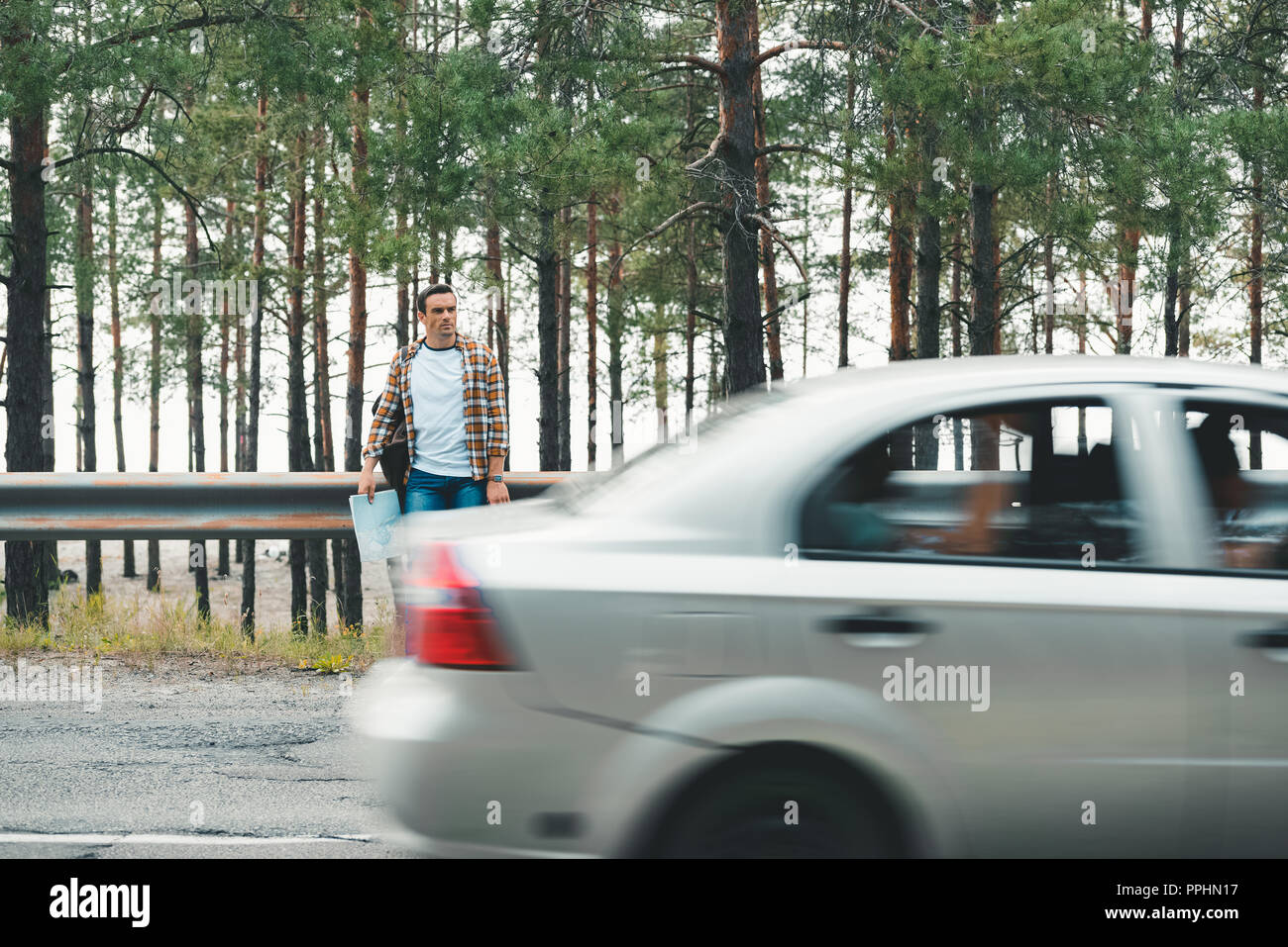 tourist with map standing on road with riding car Stock Photo - Alamy