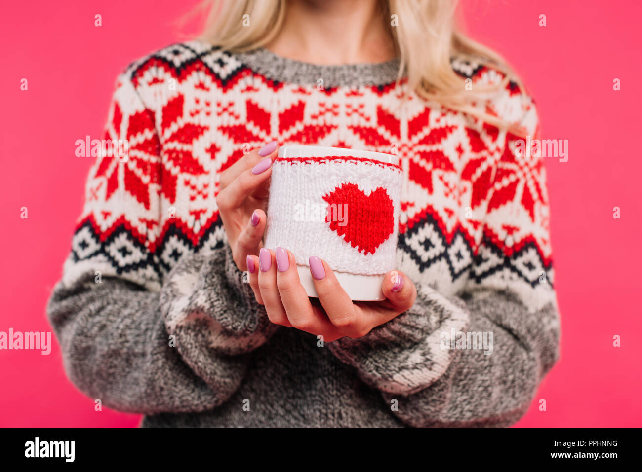 cropped image of girl in sweater holding cup with heart sign isolated ...