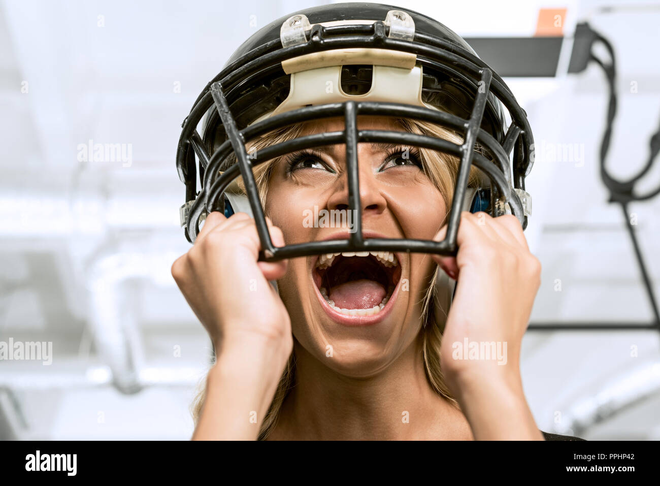 bottom view of mad young woman screaming and holding american football ...