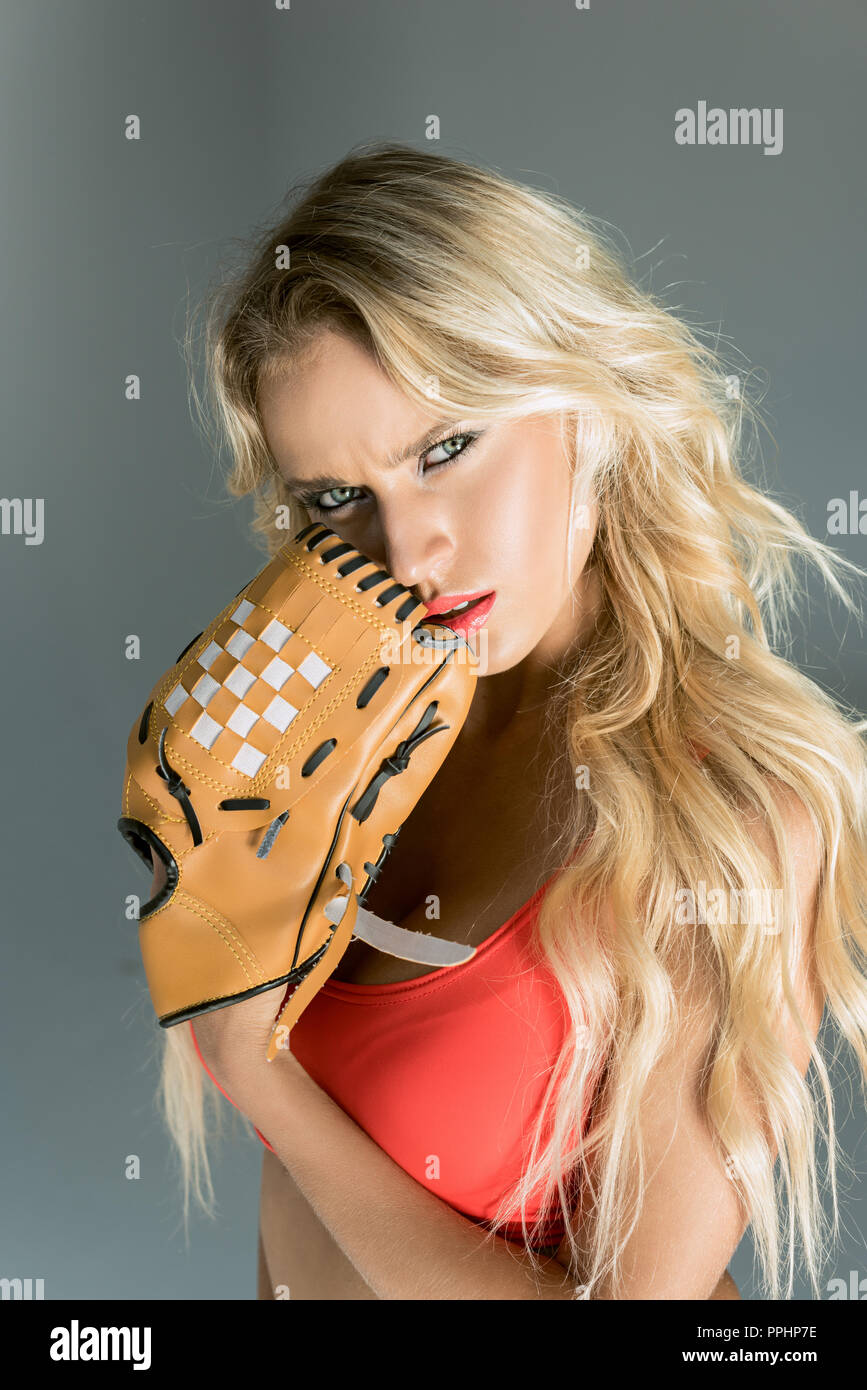 close-up portrait of serious young woman with baseball glove looking at ...
