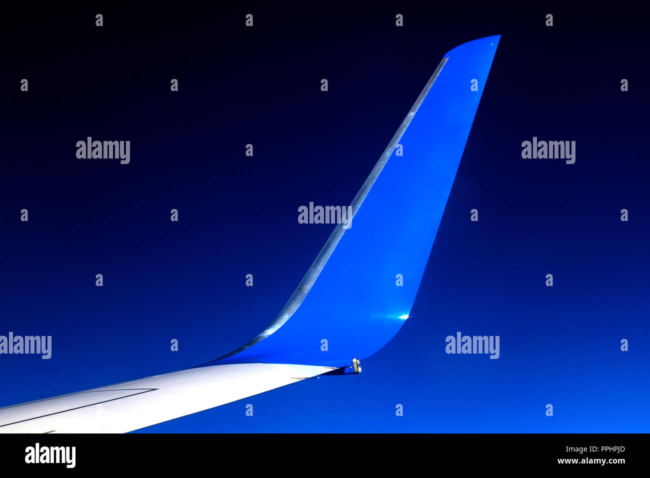 The blue winglet on a wing of plane when a flight in a blue sky. Part ...