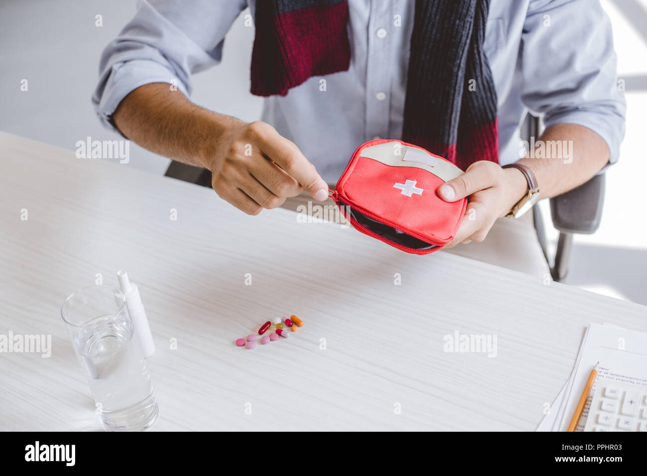 cropped image of sick manager in scarf open first aid kit in office ...