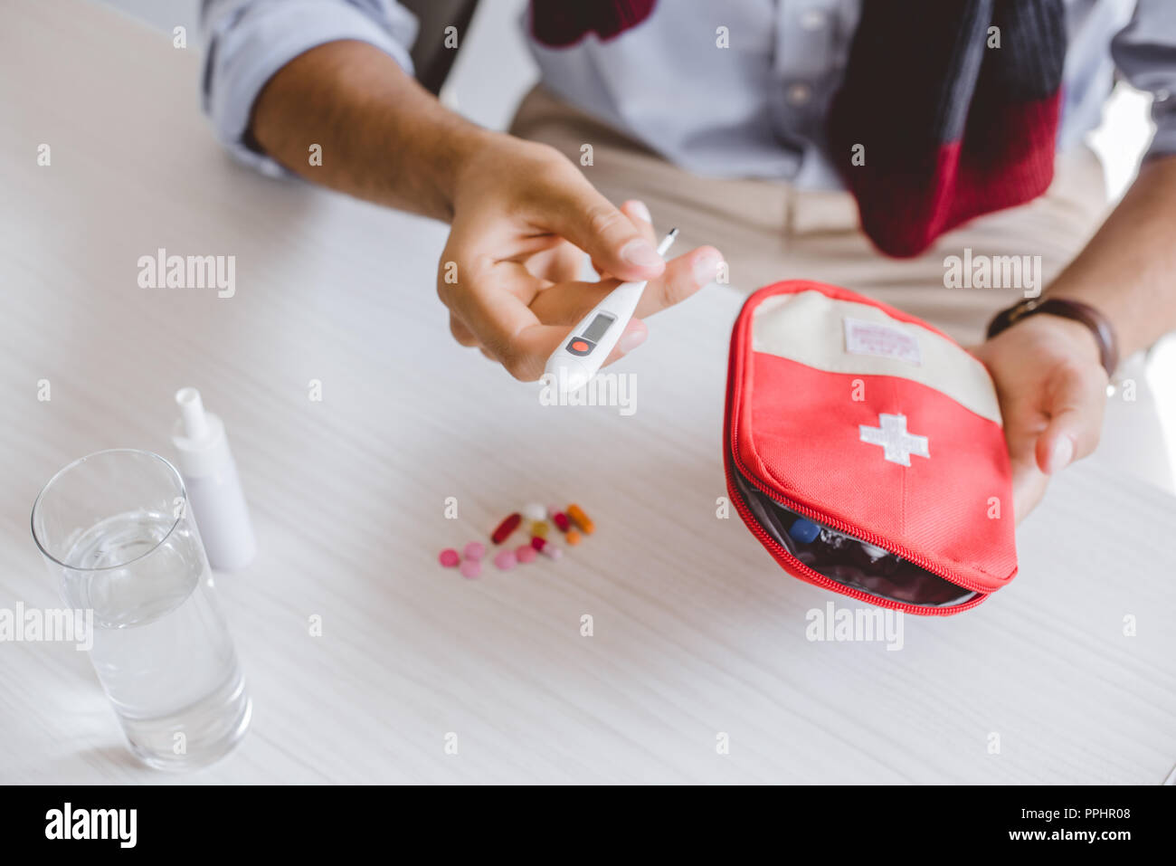cropped image of sick manager in scarf holding first aid kit and ...