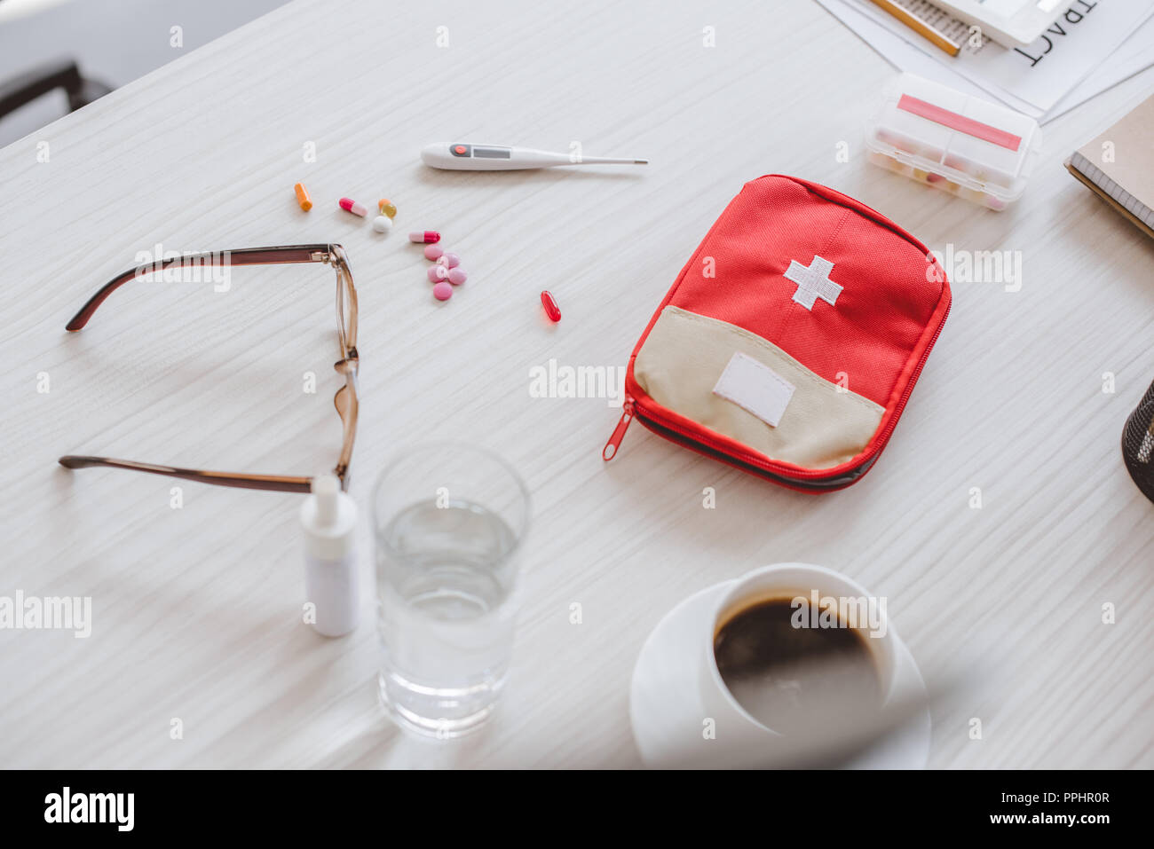 high angle view of first aid kit, glass of water, cup of coffee and ...
