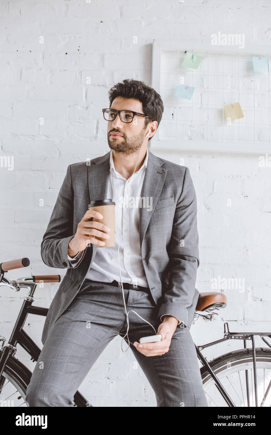 businessman listening music with smartphone, holding cup of coffee and ...