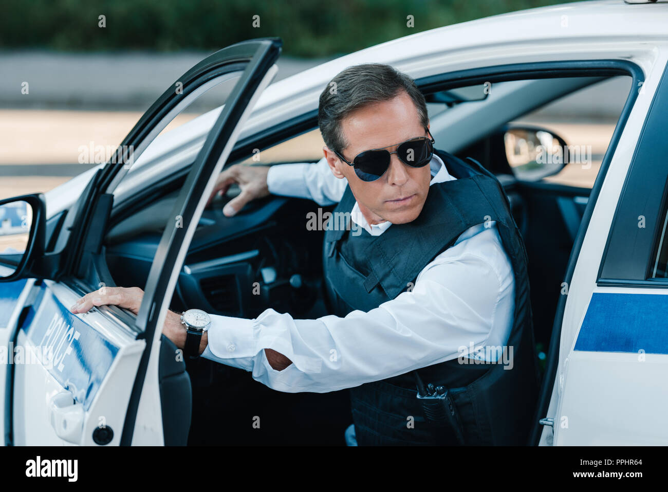 serious middle aged male police officer in bulletproof vest and ...