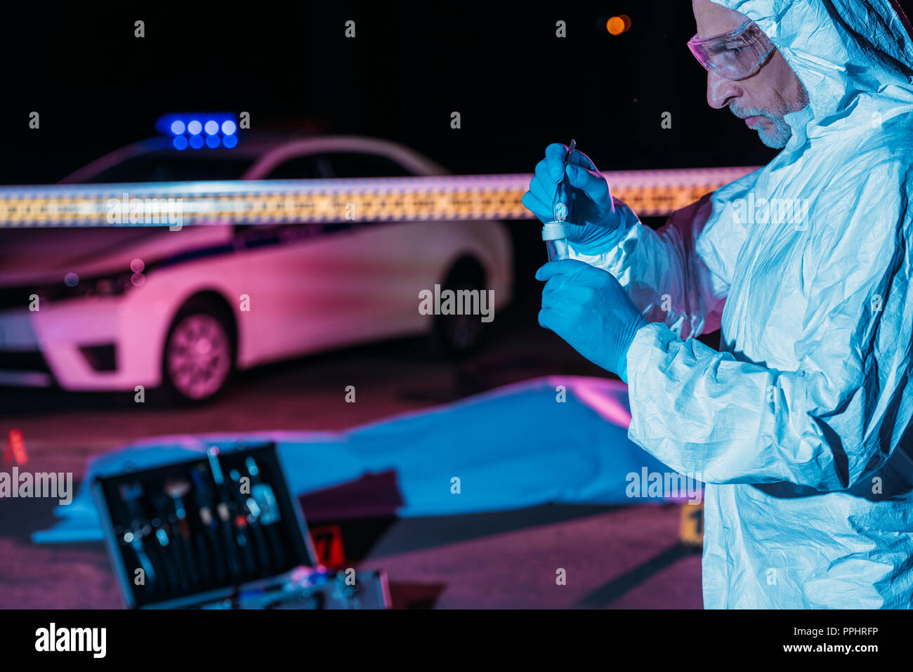Focused Male Criminologist In Protective Suit And Latex Gloves Putting