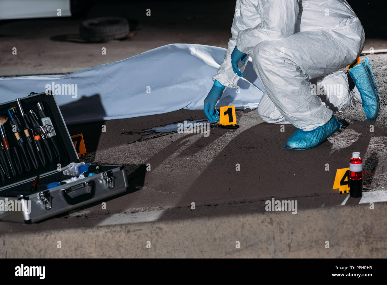 cropped image of criminologist in protective suit and latex gloves collecting evidence at crime ...