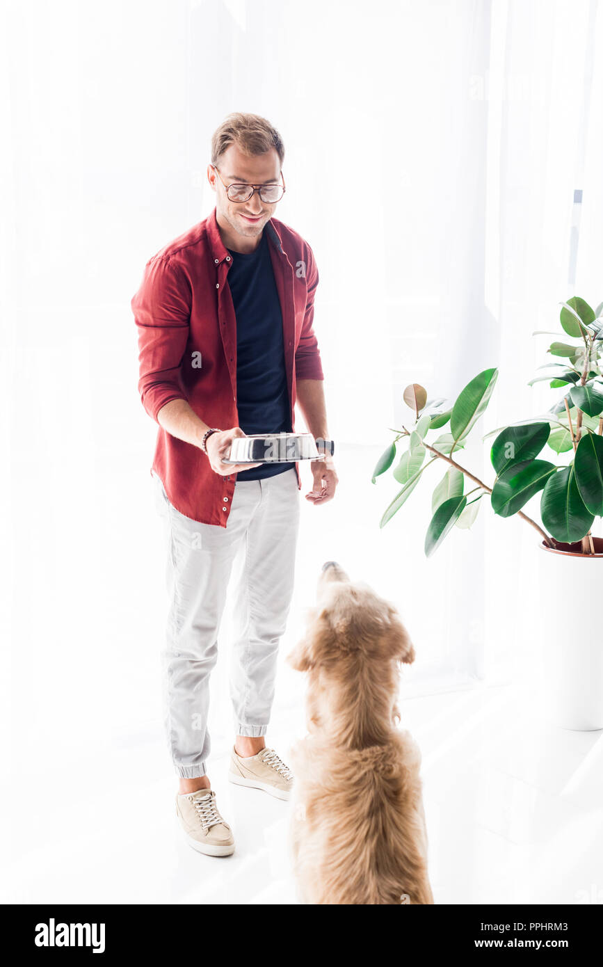 Man feeding golden retriever with dog food near plant Stock Photo - Alamy