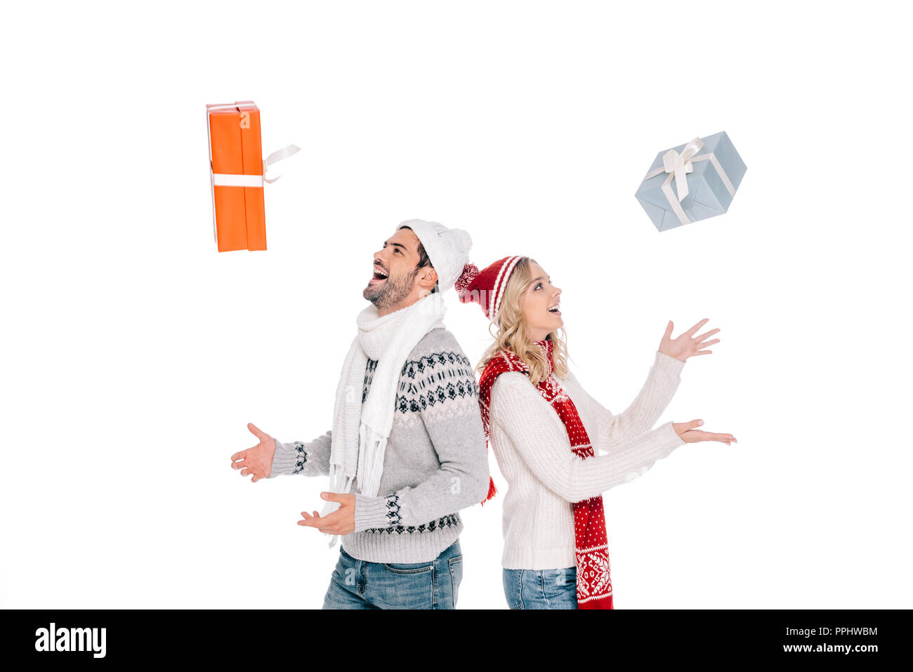 side view of happy young couple standing back to back and throwing gift ...