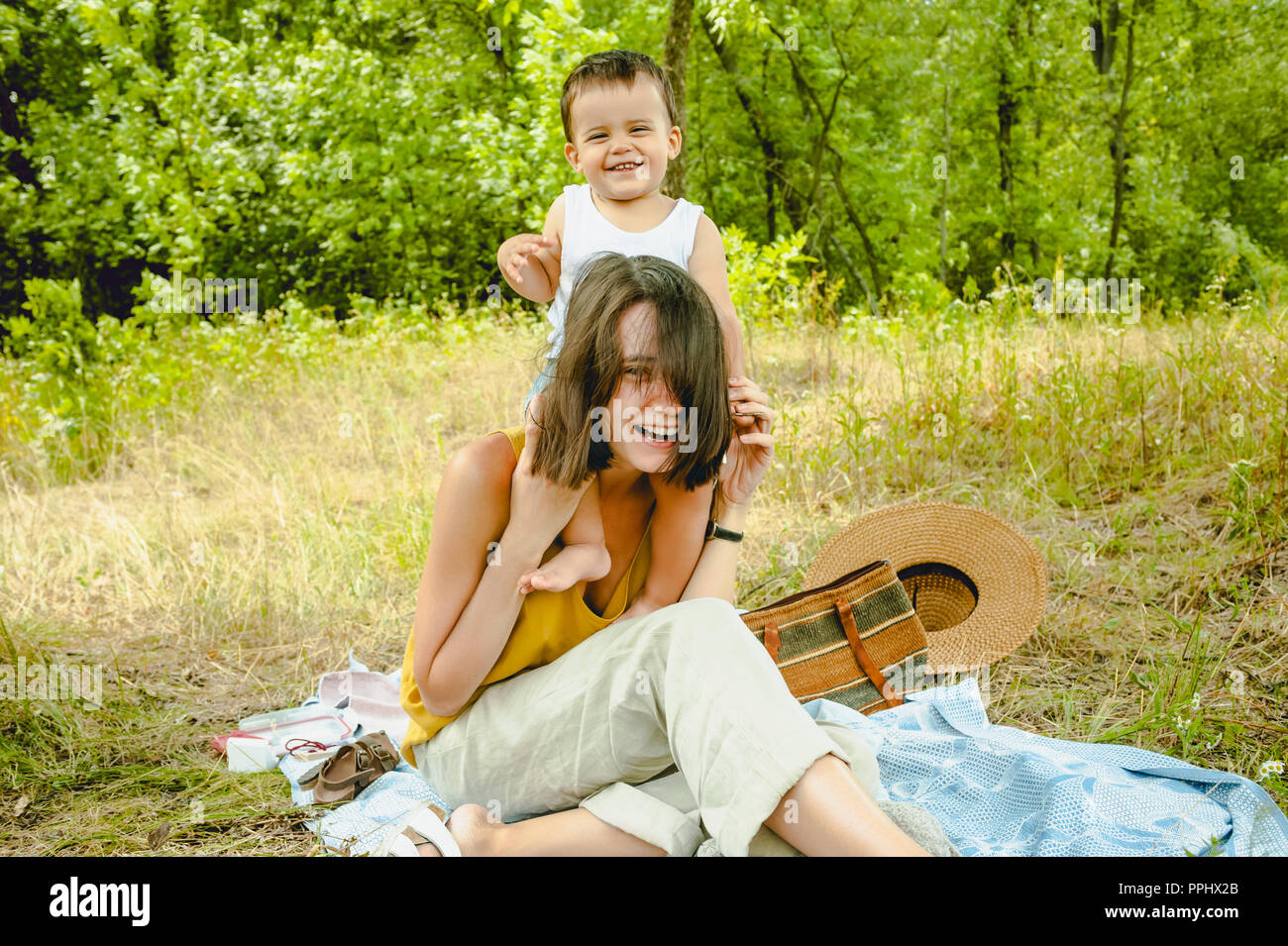 laughing mother holding son on shoulders at picnic Stock Photo - Alamy