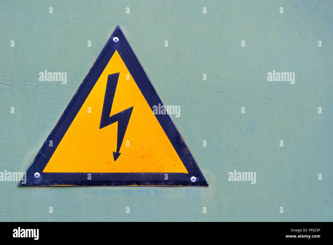The sign warning about danger of electricity on a light green ...