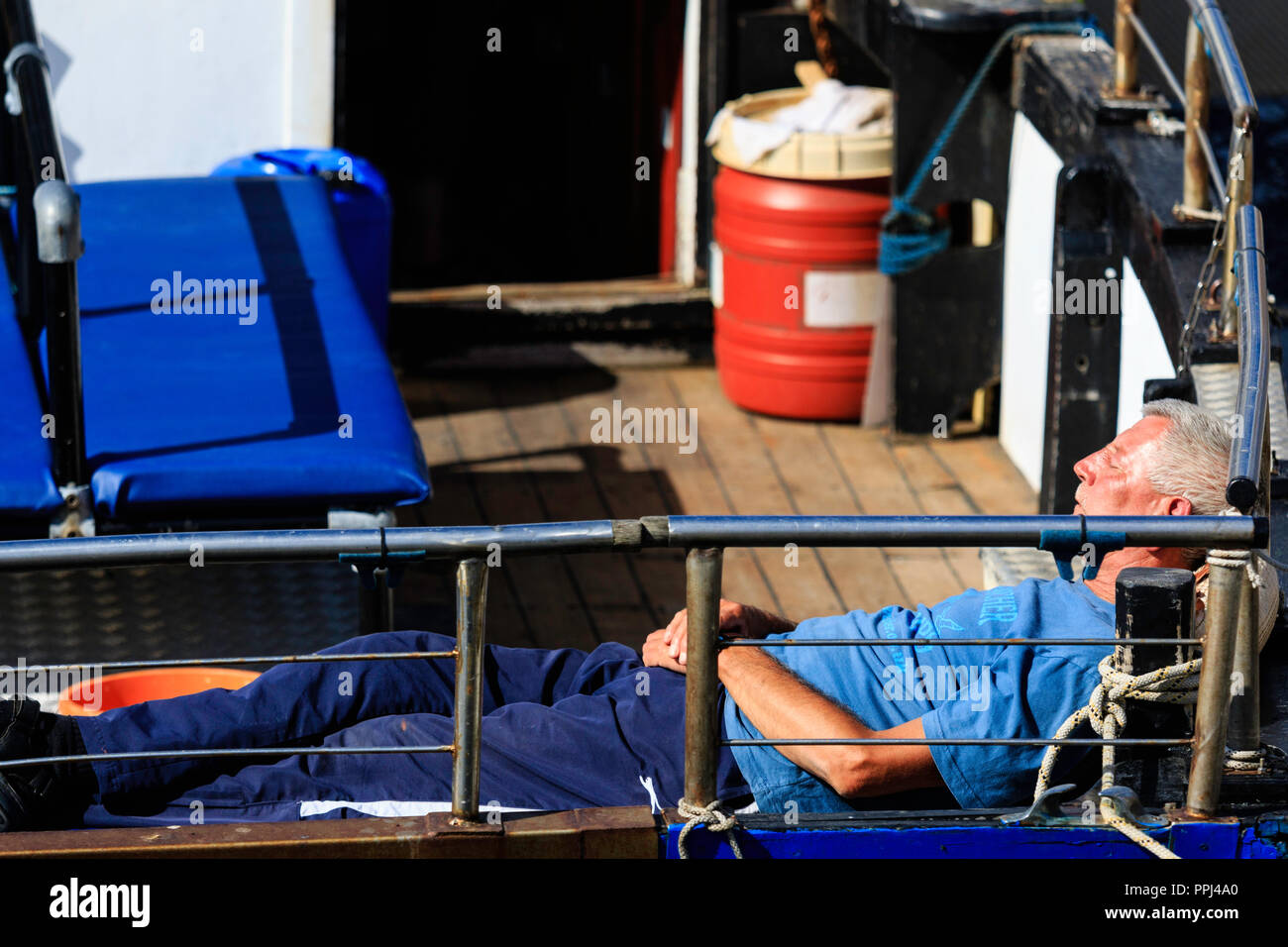 Candid of mature man asleep in the stern of his boat. Laying on his ...