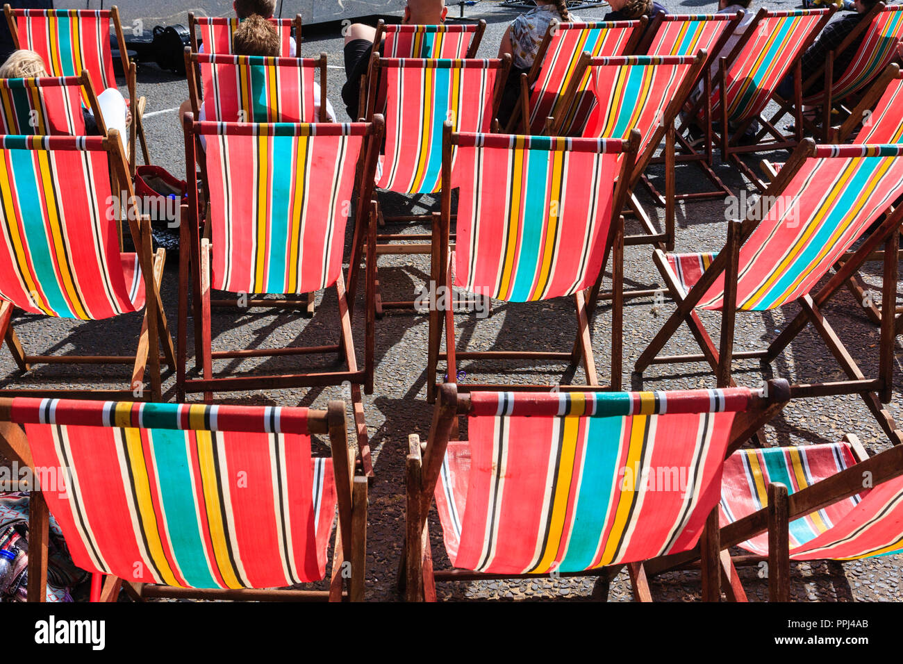 Four rows of deckchairs back lit by bright sunshine. First two rows ...