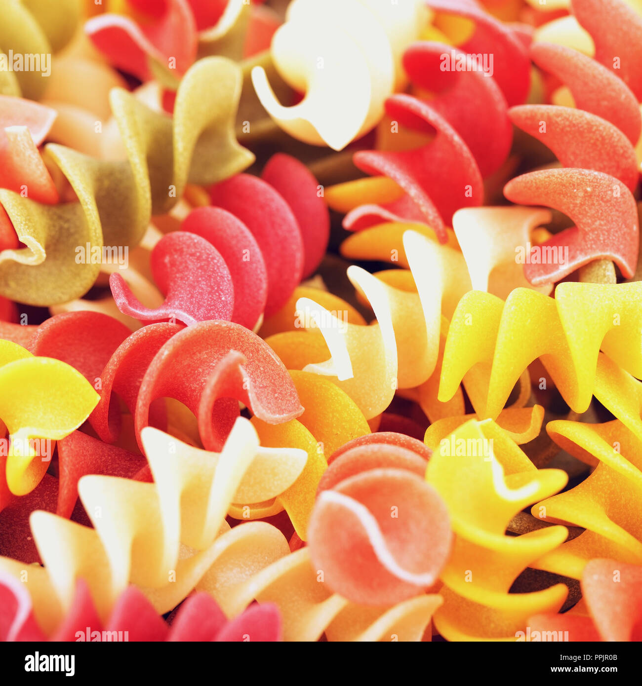 raw spiral pasta of different color, background Stock Photo - Alamy