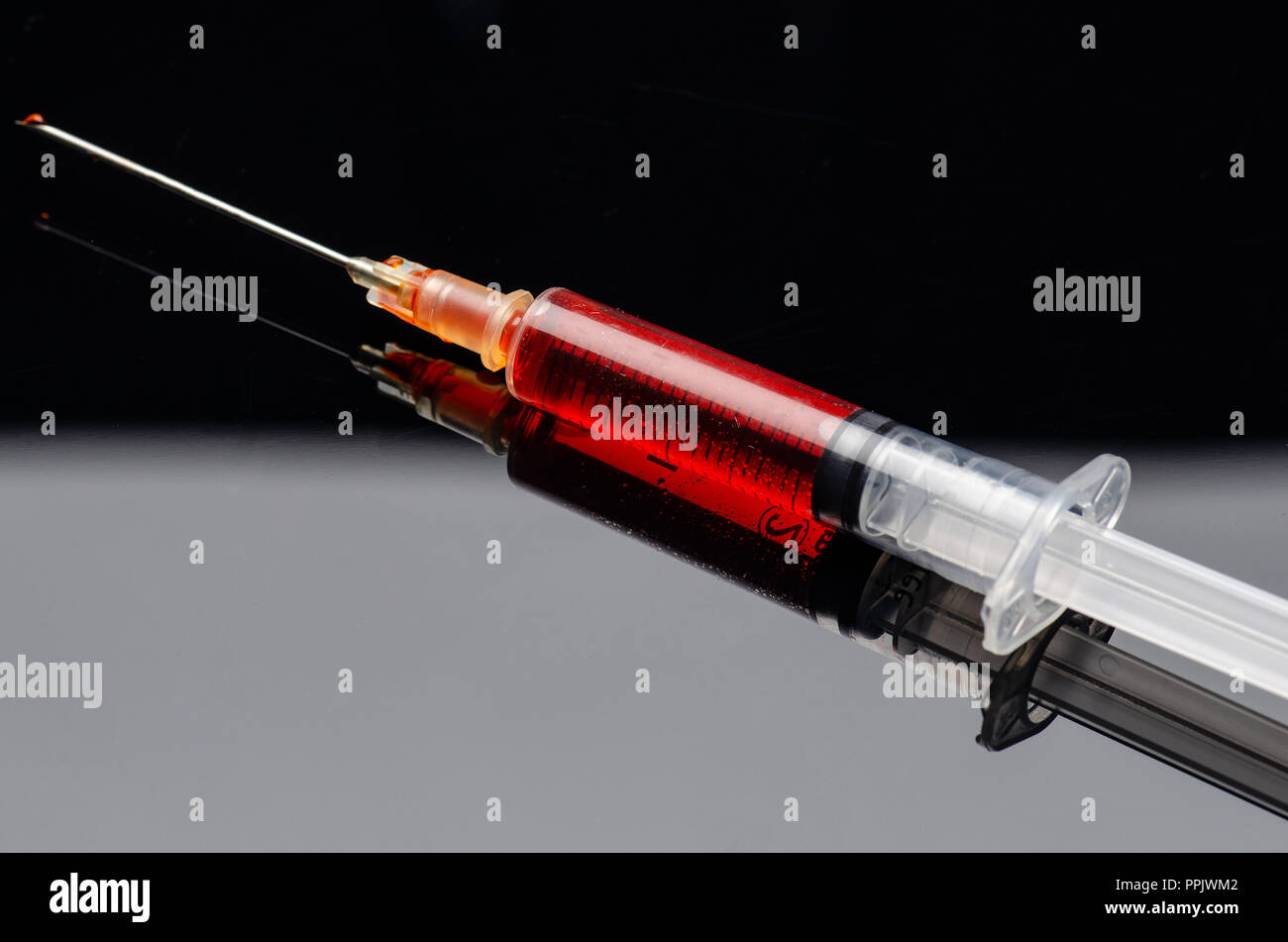 syringe filled with a red liquid on a black acrylic background Stock ...