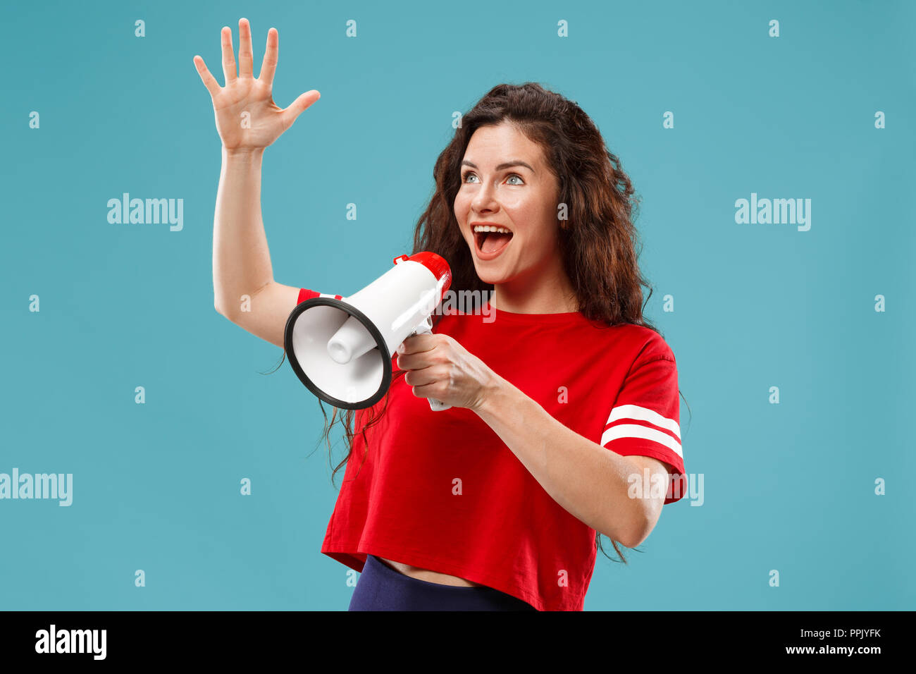 Woman making announcement with megaphone at blue studio. Human facial ...