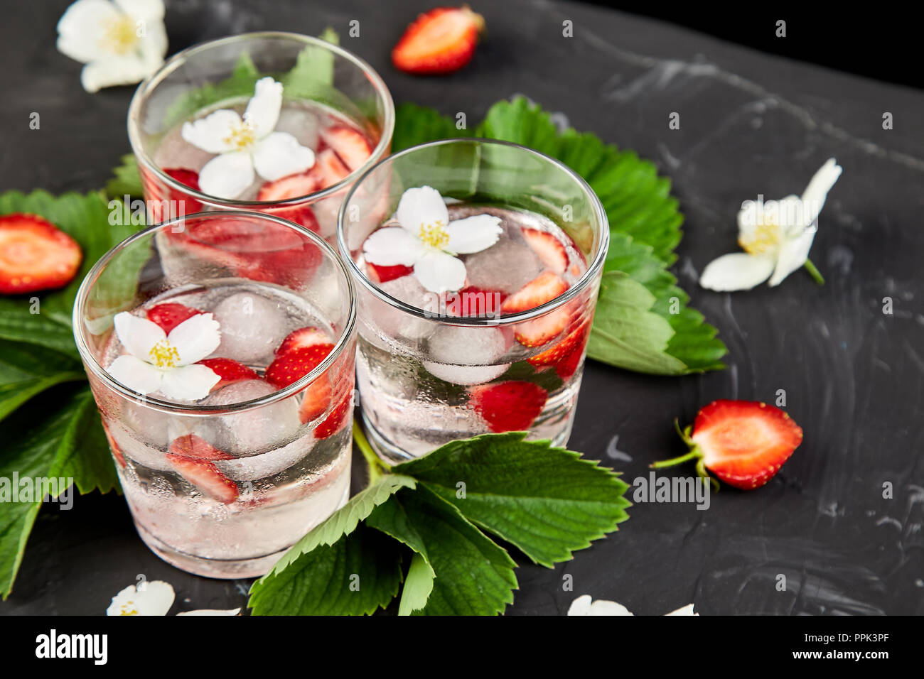 Strawberry detox water with jasmine flower. Summer iced drink or tea ...