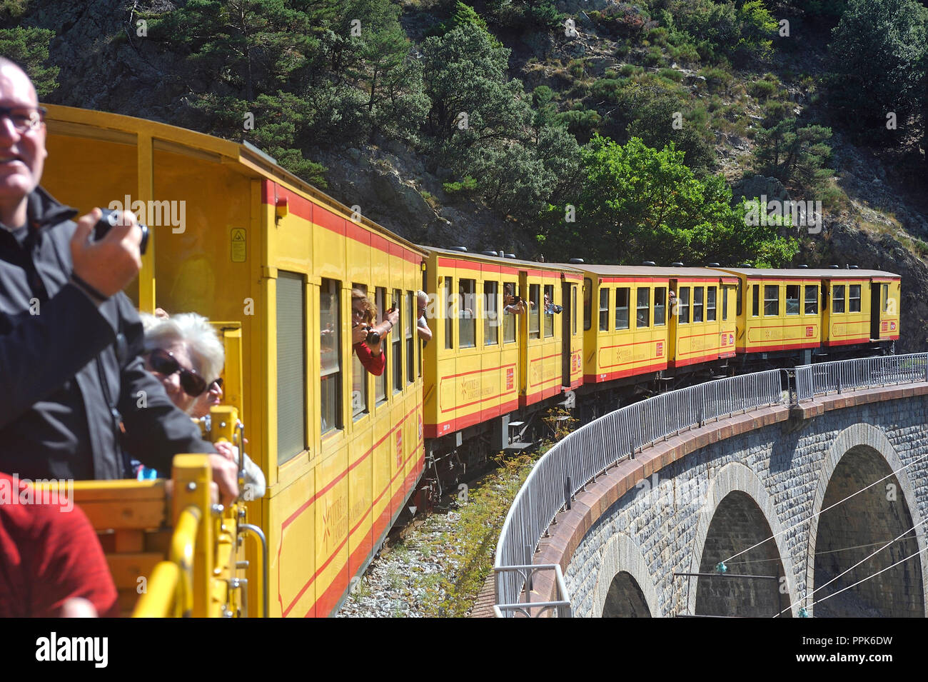 The small yellow trains of the Pyrenees crossing a beautiful mountain ...