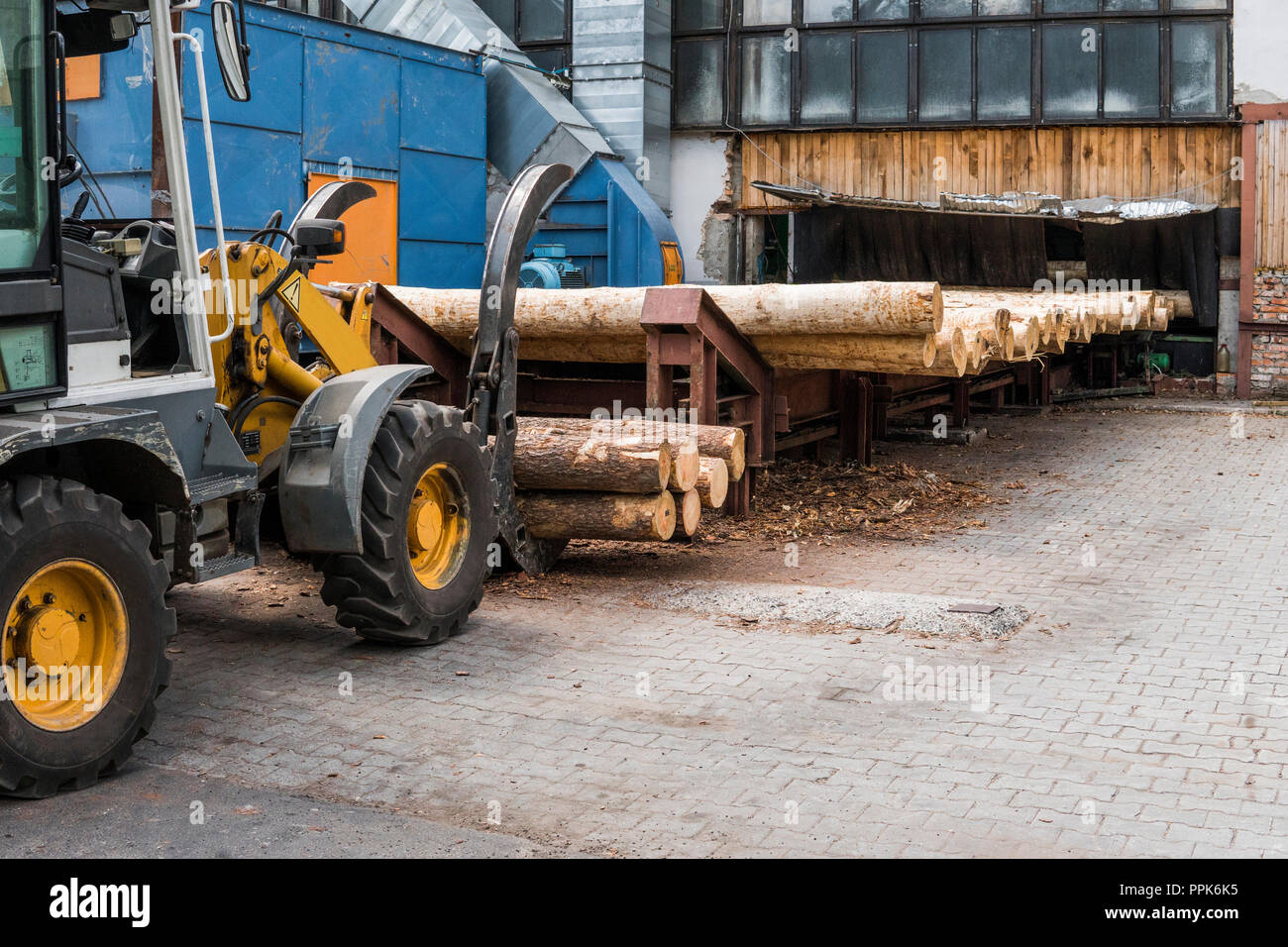 Forklift truck grabs wood in a wood processing plant. Large log loader ...