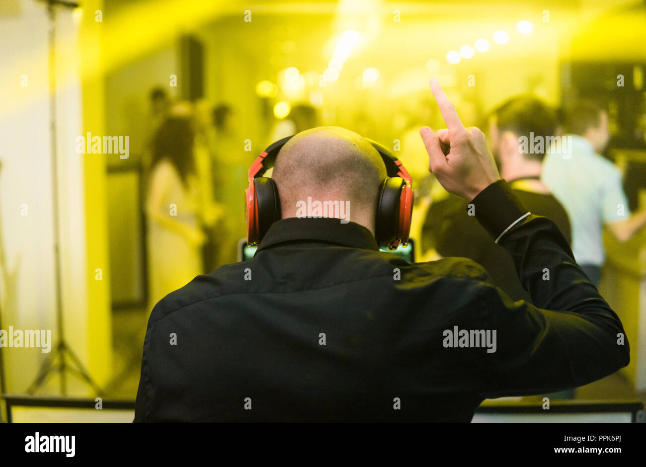 DJ with red headphones at night club party under the yellow light and ...