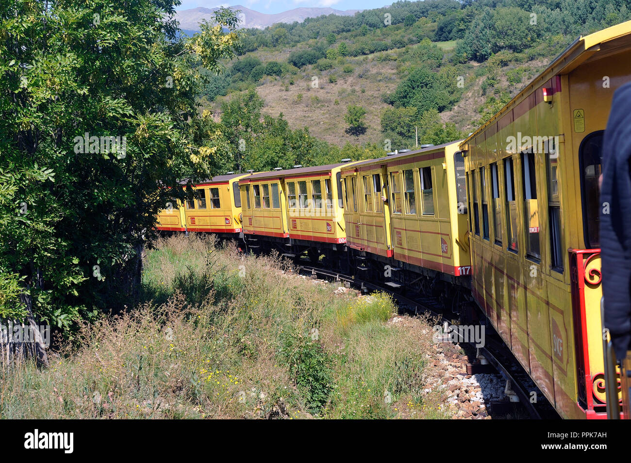 The small yellow trains of the Pyrenees crossing a beautiful mountain ...