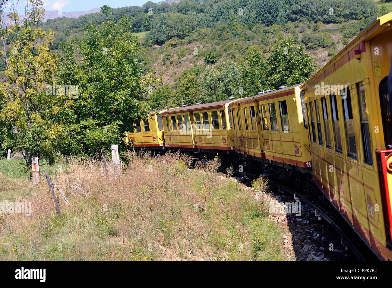 The small yellow trains of the Pyrenees crossing a beautiful mountain ...