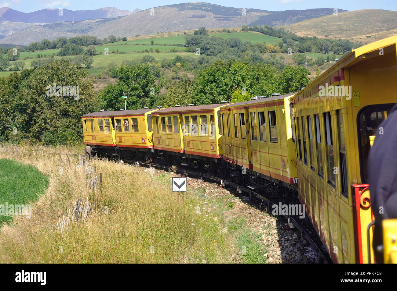 The small yellow trains of the Pyrenees crossing a beautiful mountain ...
