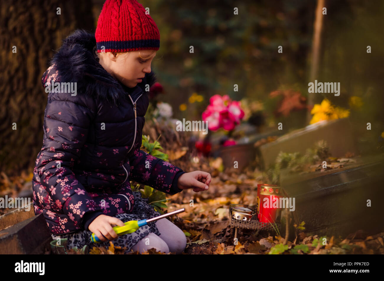 child burning candle during All Saints Day at the cemetery Stock Photo ...