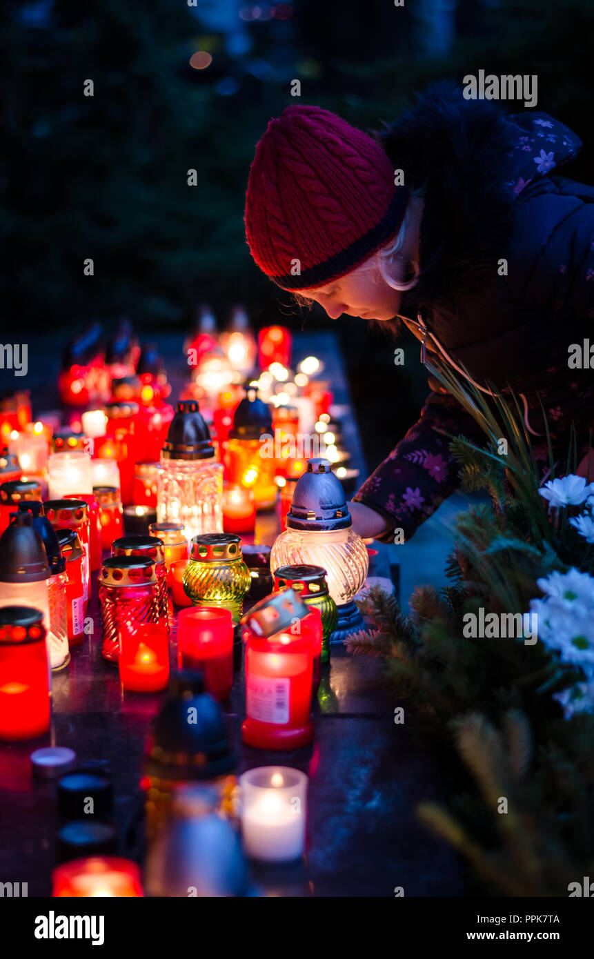 child burning candle during All Saints Day at the cemetery at dark ...
