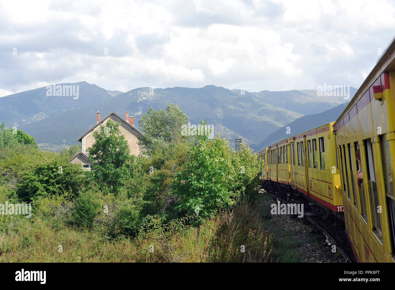 The small yellow train of the Pyrenees crossing a beautiful mountain ...