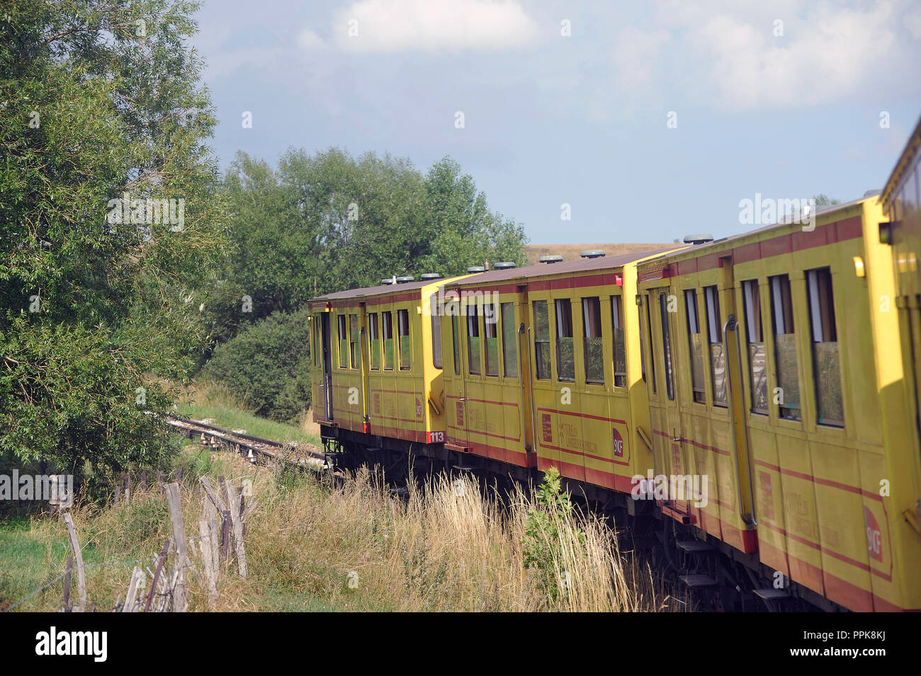 The small yellow train of the Pyrenees crossing a beautiful mountain ...