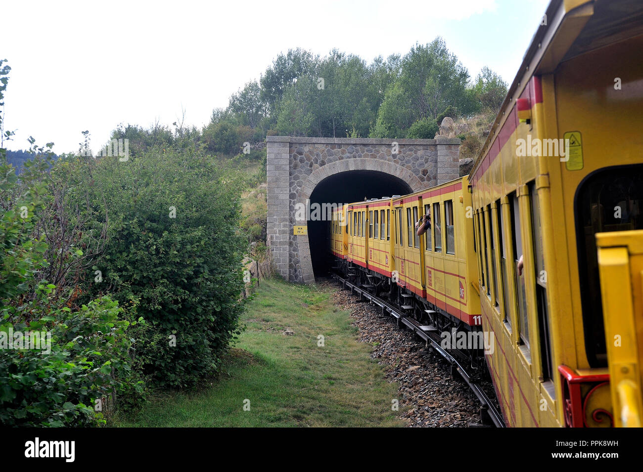 The small yellow train of the Pyrenees crossing a beautiful mountain ...