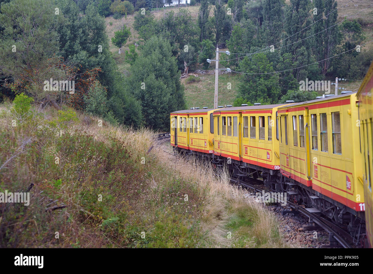 The small yellow train of the Pyrenees crossing a beautiful mountain ...